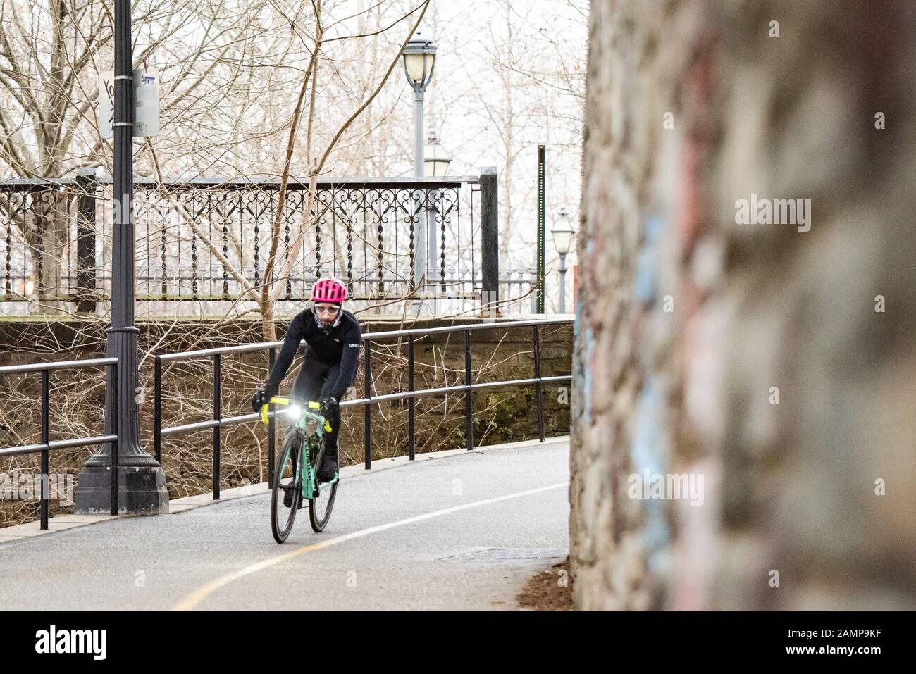 A cyclist in black tights and pink helmet rides around a corner Stock ...