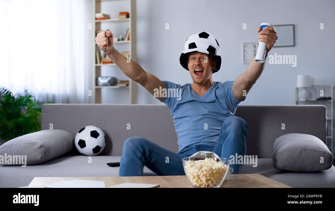 Ardent football supporter in fan hat rejoicing to scored penalty kick ...