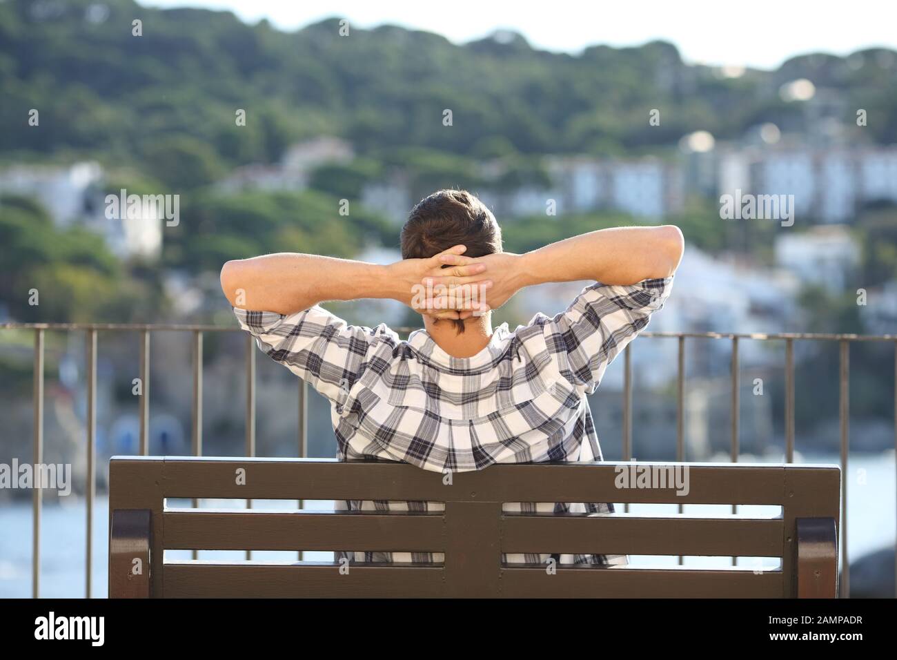 Back view portrait of a man relaxing contemplating views sitting on a ...