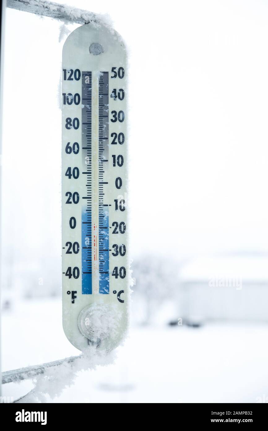 A vertical large outdoor temperature gauage surrounded by frost along ...