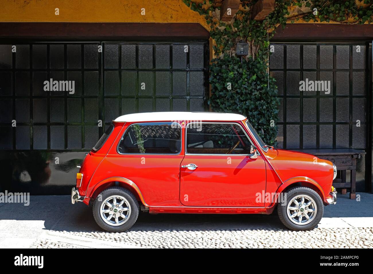 Red Austin Mini with a white roof, stands on a cobble-stoned courtyard ...