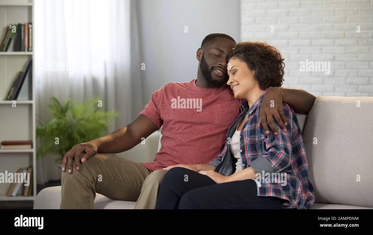 Tender multiracial couple hugging, having rest in home comfort, happy ...