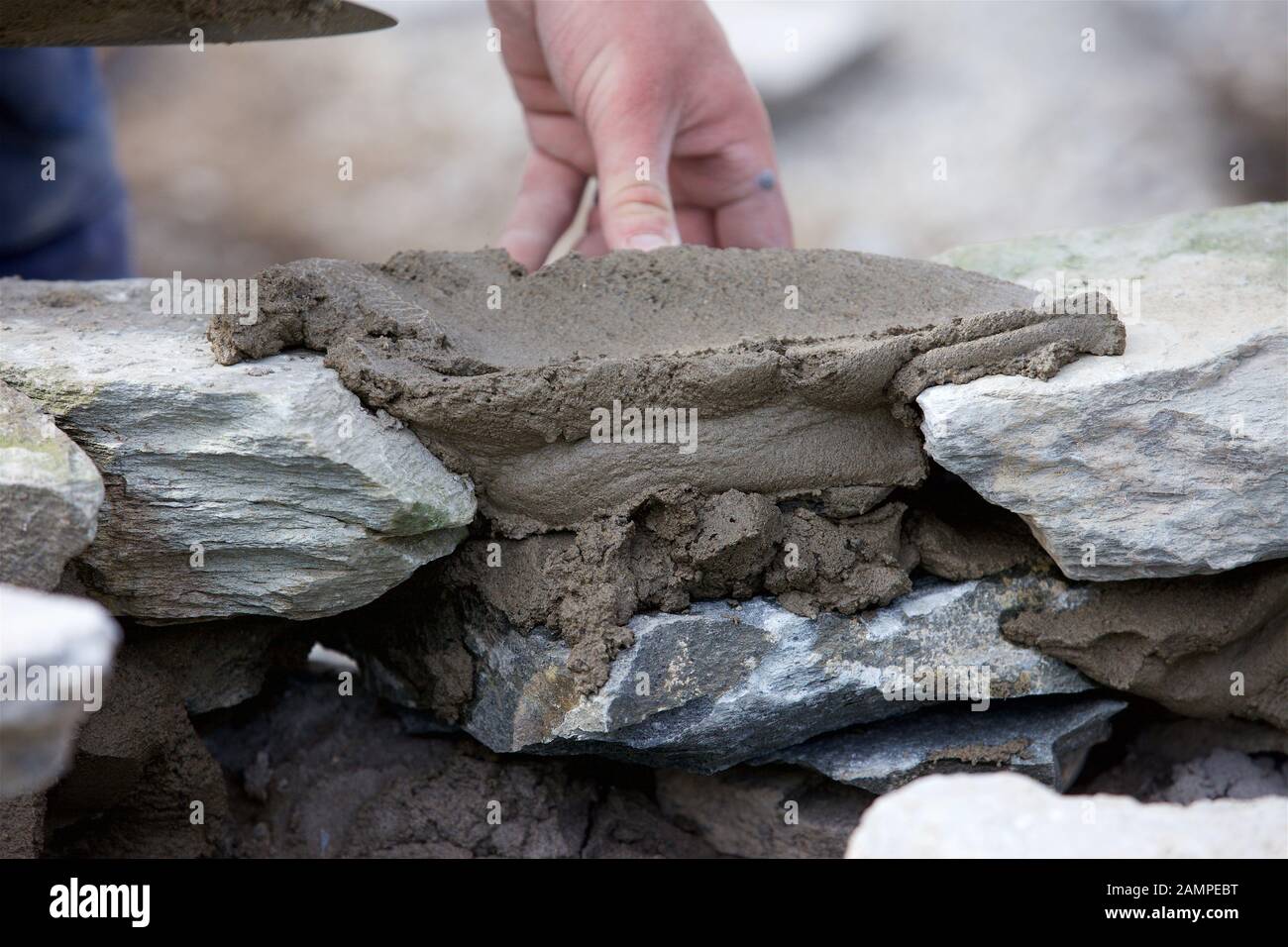 Close-up shot of a stonemason building a stone wall Stock Photo - Alamy