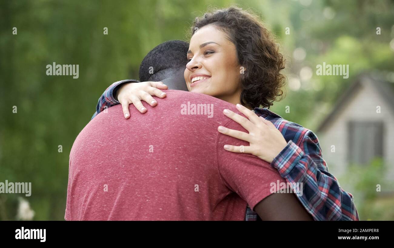 Supportive wife meeting husband in front of home and giving him welcome ...