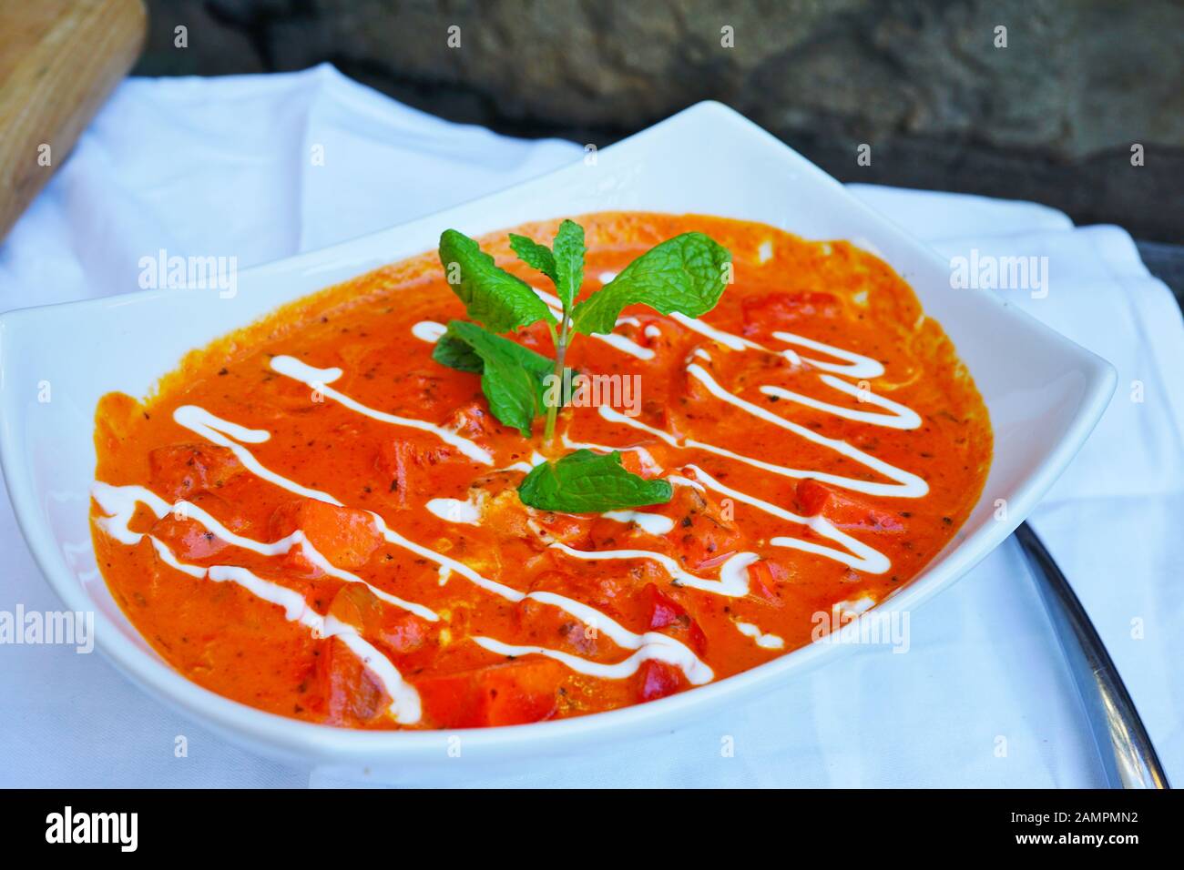 A dish of butter chicken tikka masala in red sauce at an Indian ...