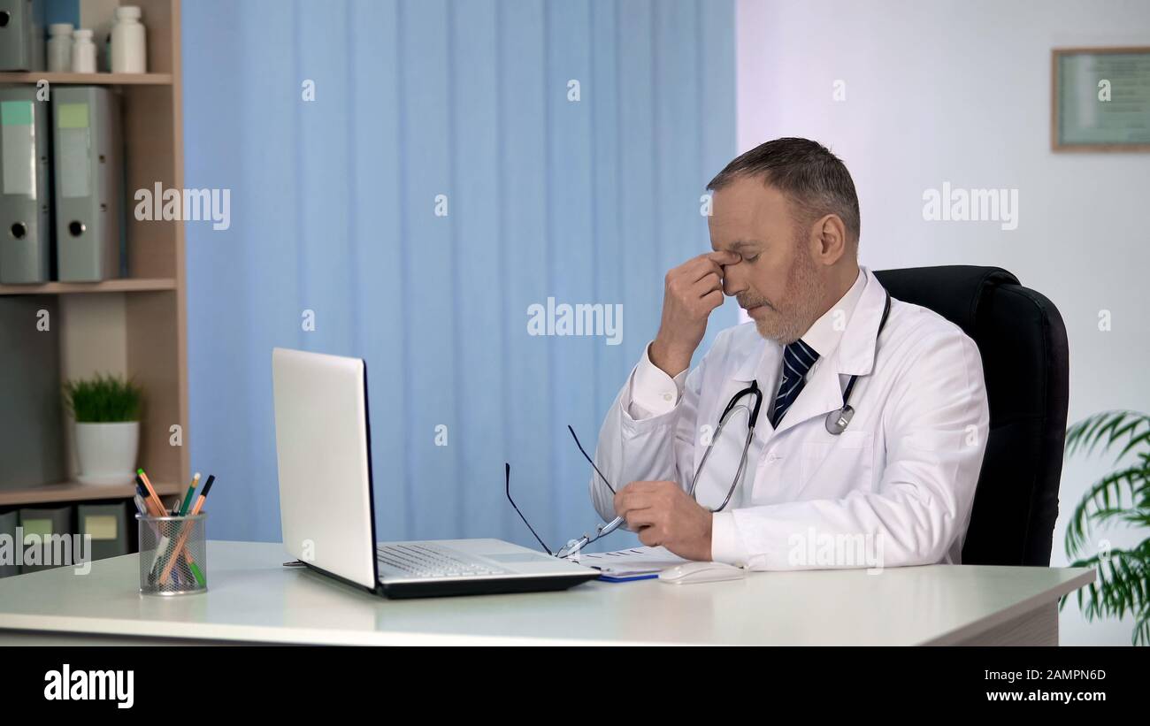 Tired doctor rubbing eyes, hard working day, viewing medical records of ...