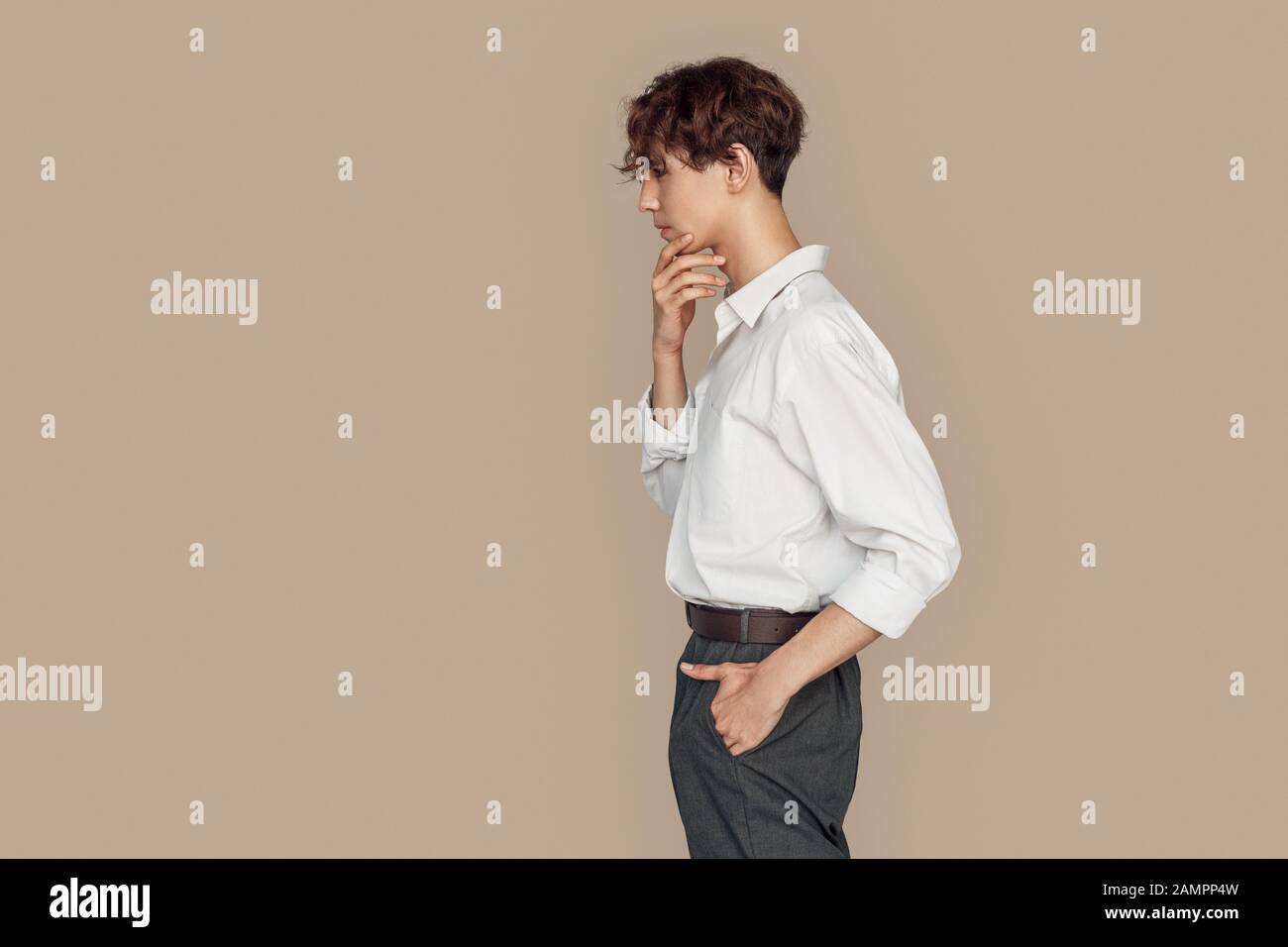 Freestyle. Man in formal wear standing isolated on gray hand in pocket ...