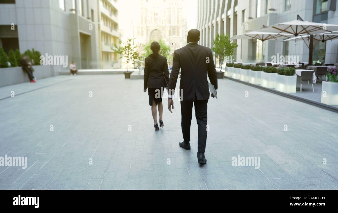 Rich business lady walking followed by bodyguard, successful lady, back ...