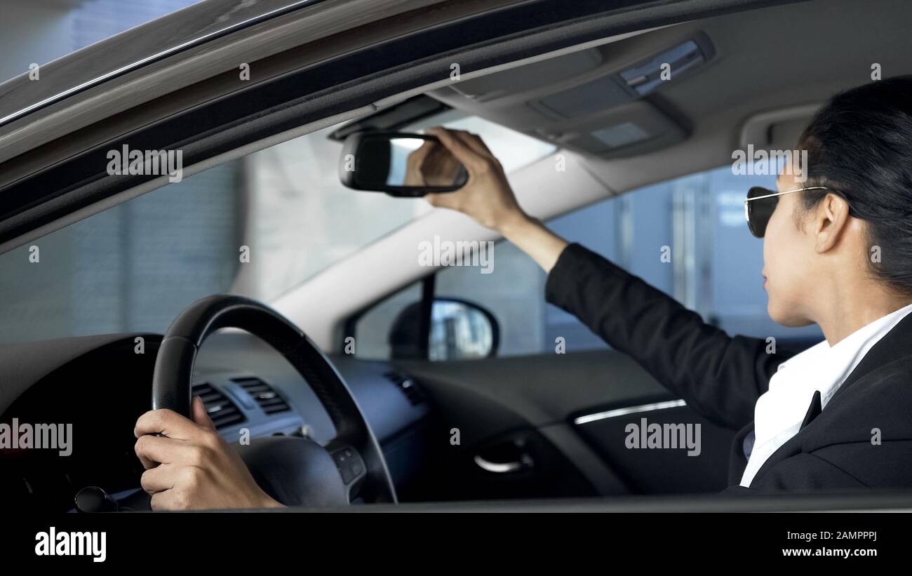 Business lady looking in rear-view mirror, driving automobile, traffic ...