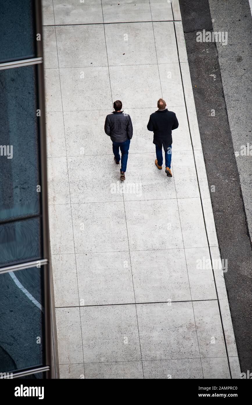 Low-angle view of two men walking along a sidewalk Stock Photo - Alamy
