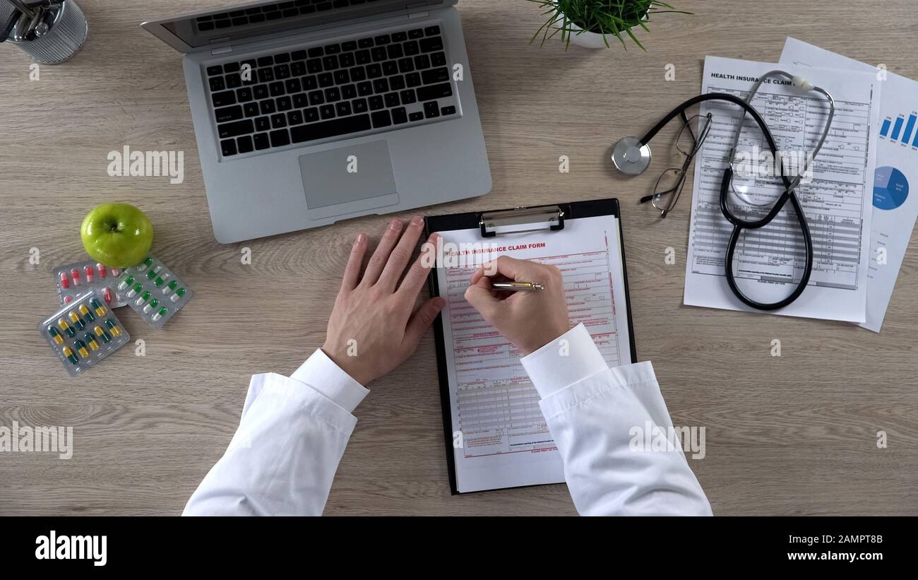 Top view of general practitioner filling health insurance claim form ...