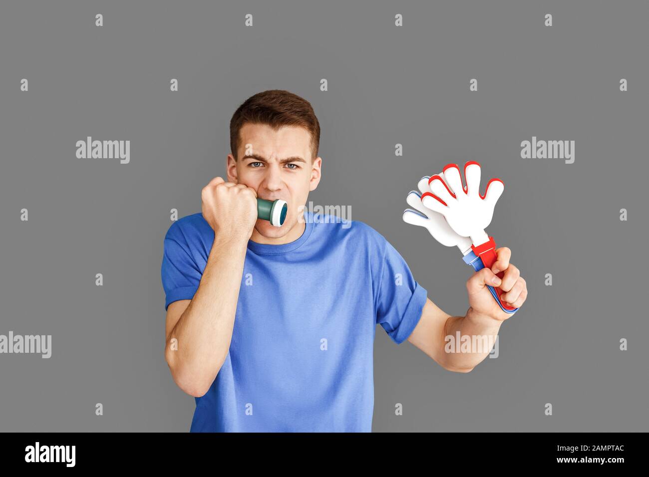 Freestyle. Young man standing isolated on grey making sound with noise ...
