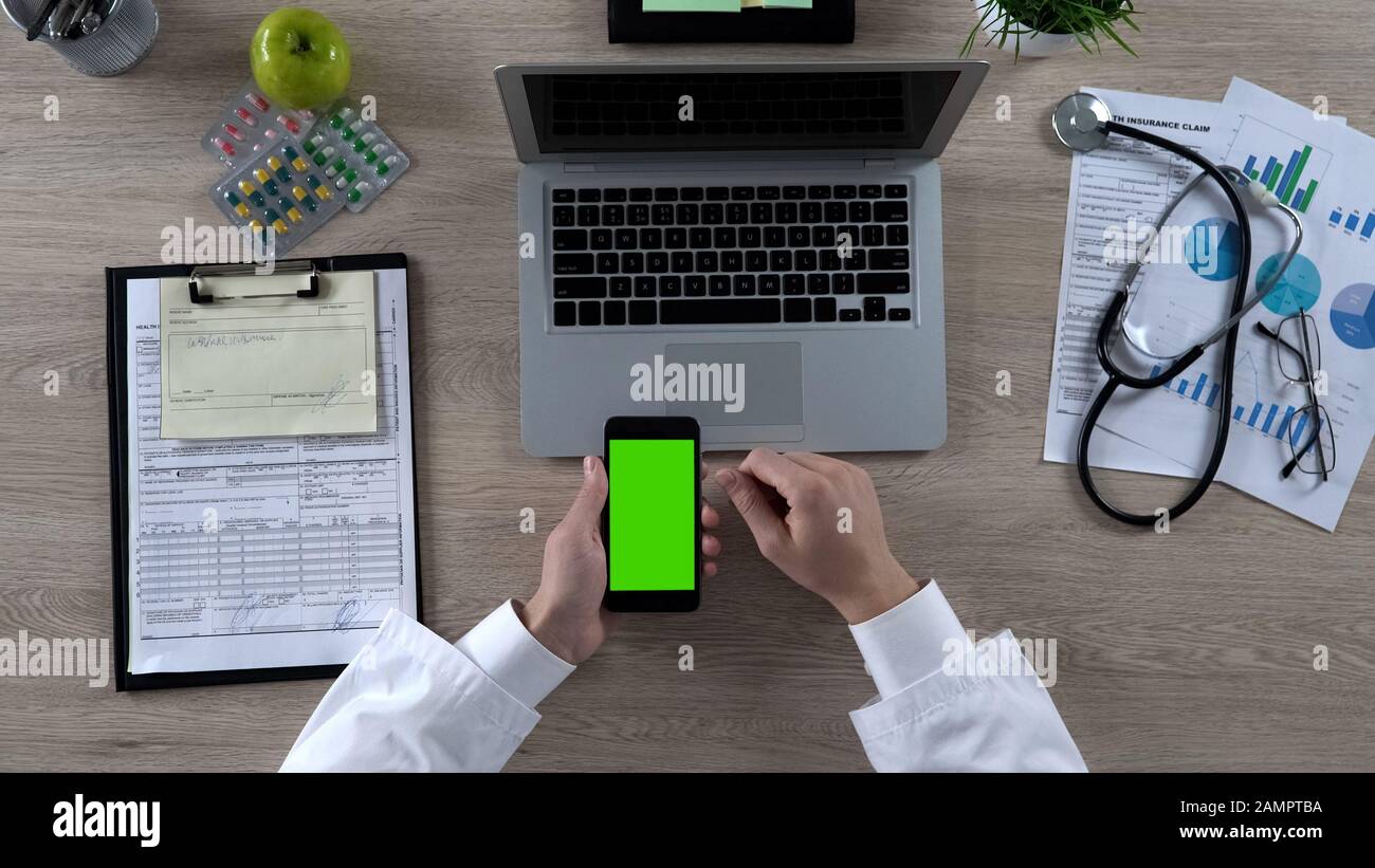 Doctor scrolling green screen smartphone, viewing test results in ...