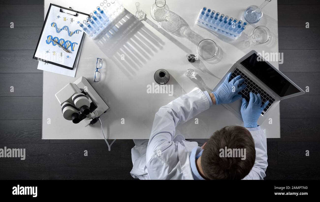 Chemist writing down results of chemical experiments on computer, top ...