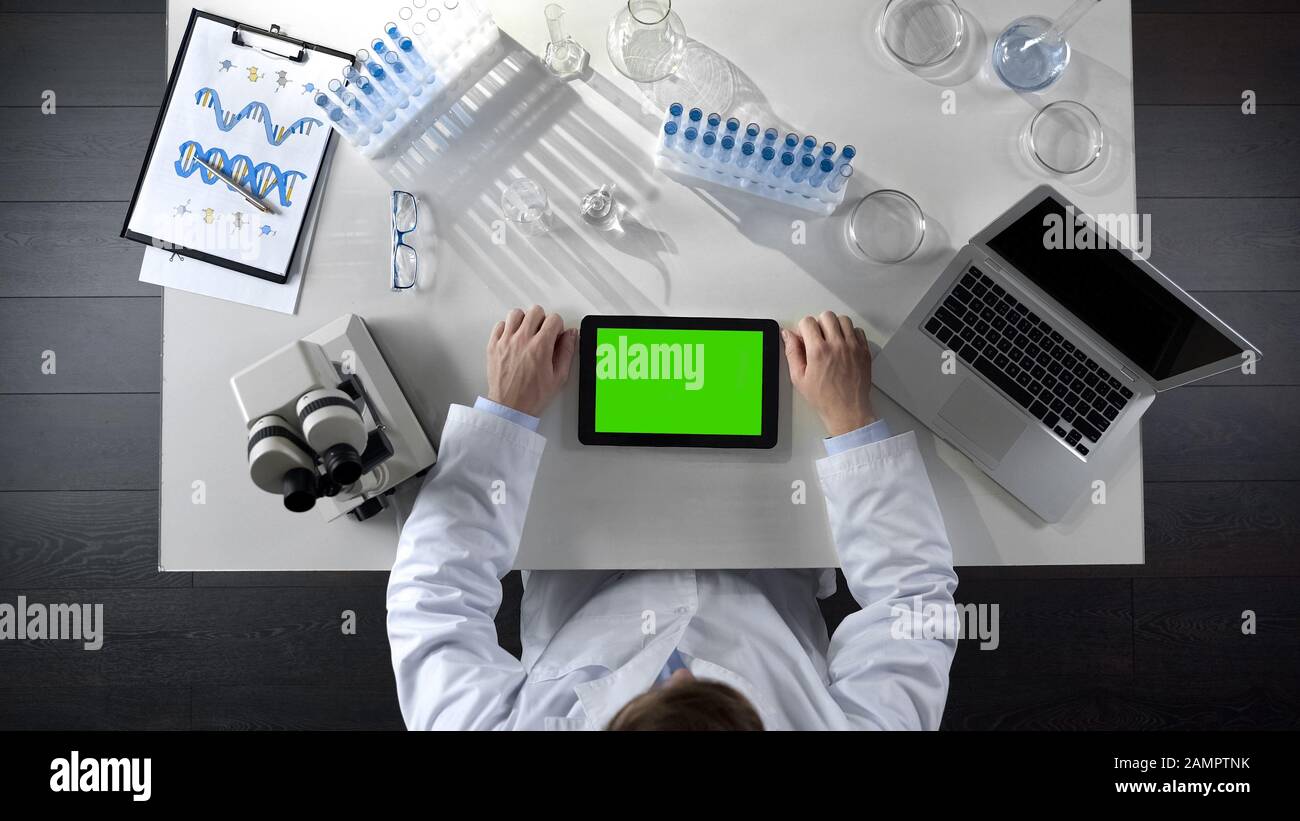 Top view of laboratory worker scrolling tablet with green screen ...