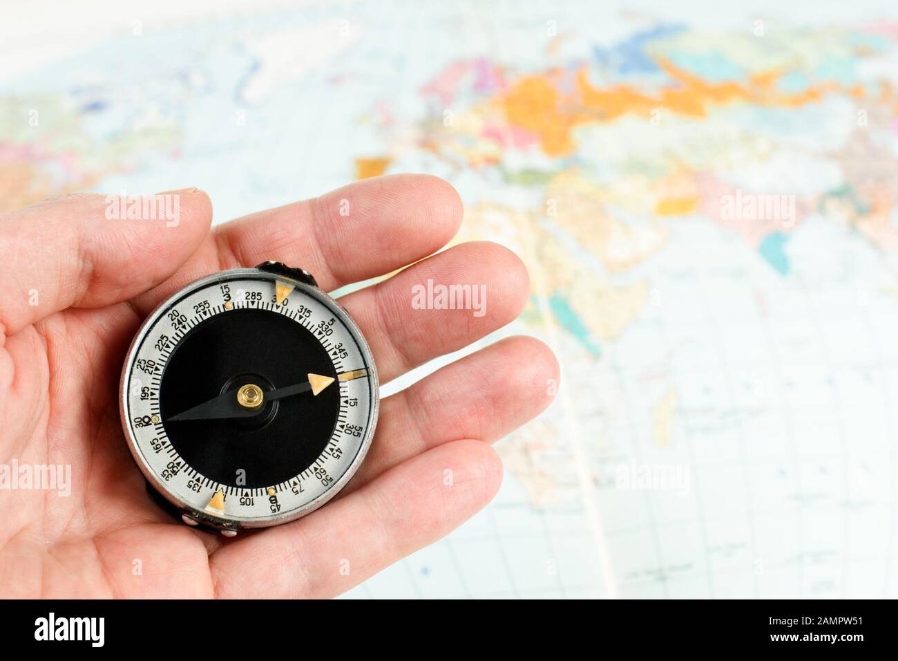 Hand holding compass with map of the world in background Stock Photo ...