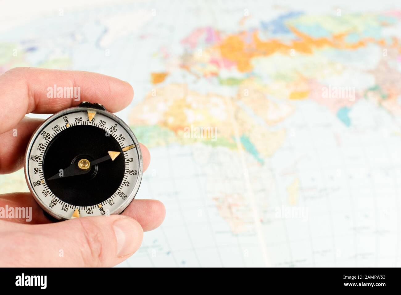 Hand holding compass with map of the world in background Stock Photo ...