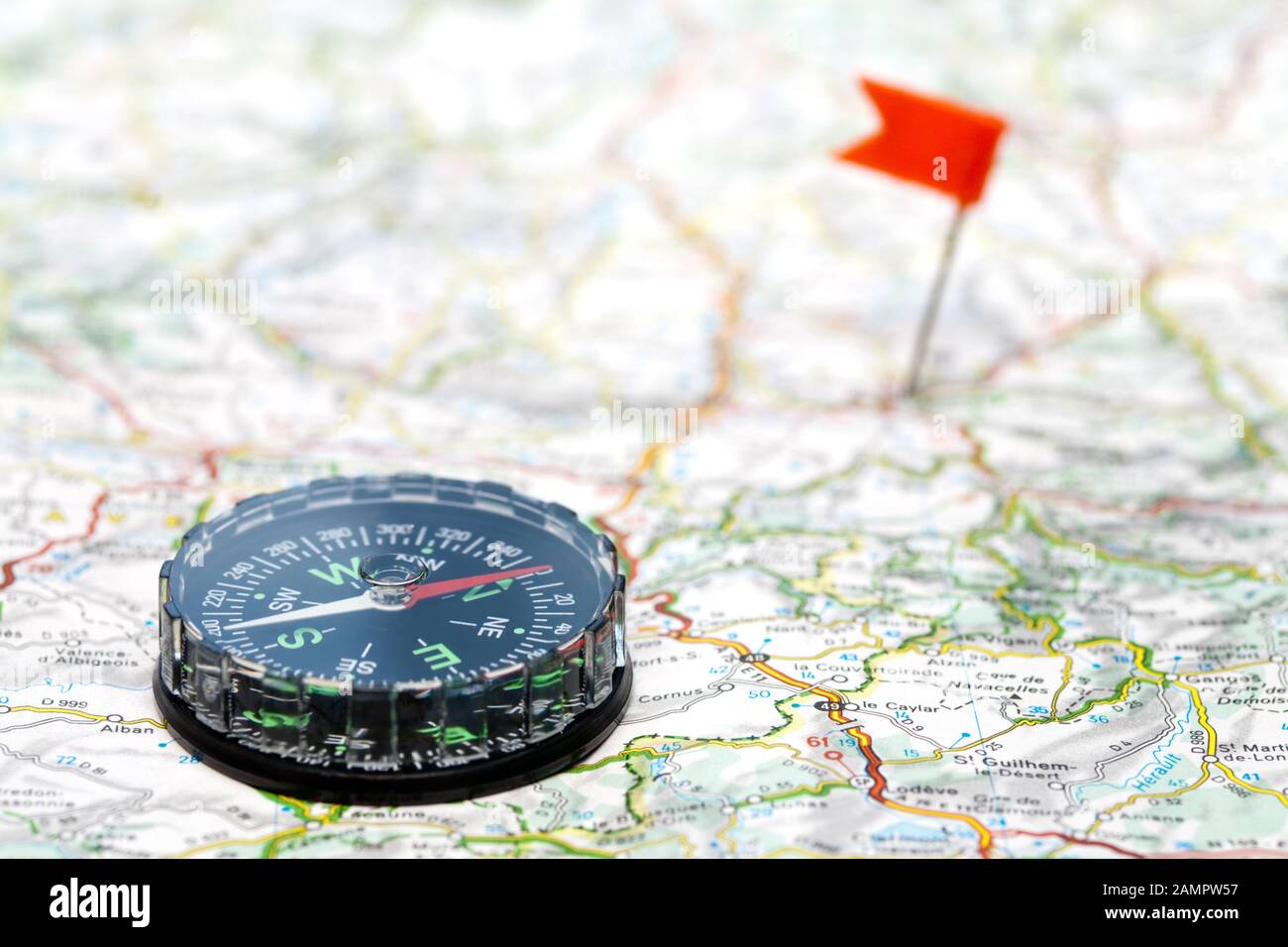 Compass on map with color flag pin in background Stock Photo - Alamy