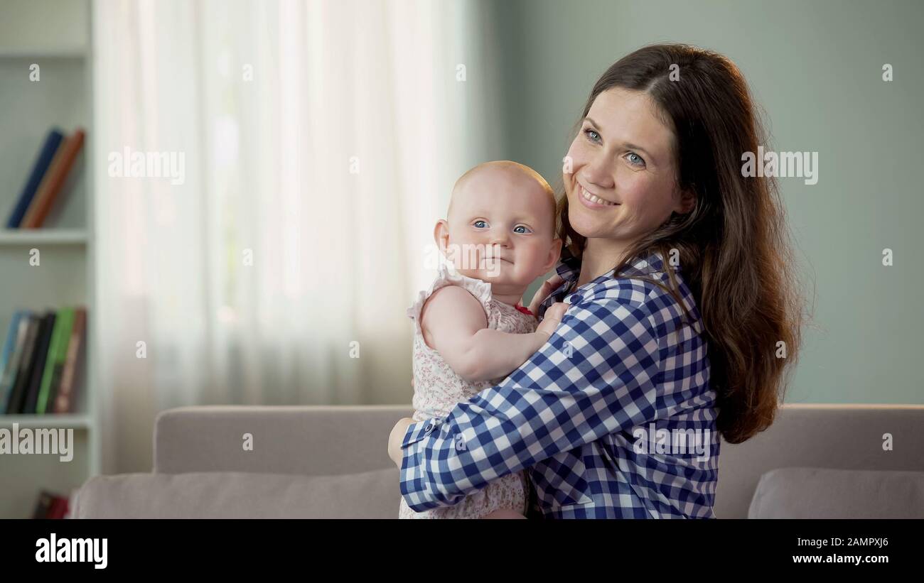 Pretty young mother and cute baby daughter hugging and smiling, happy ...