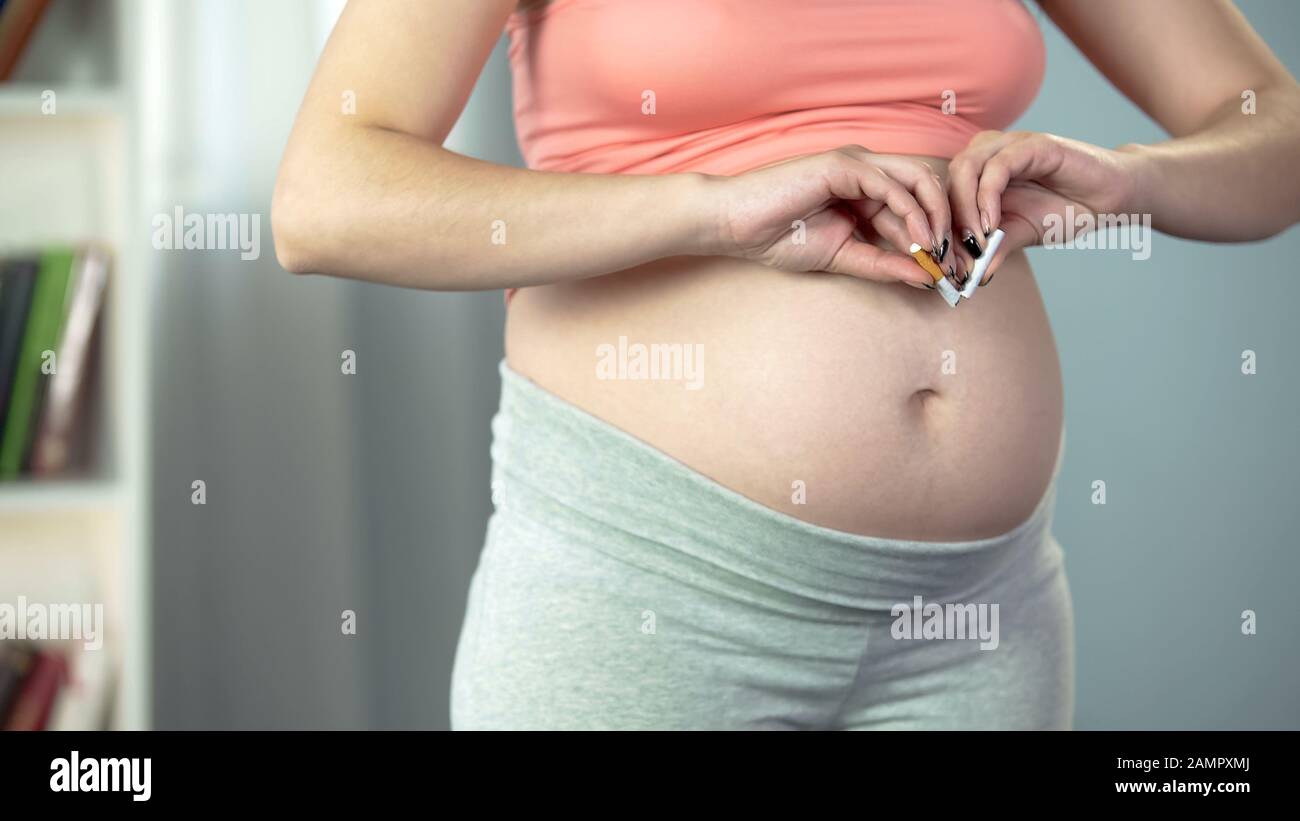 Pregnant woman breaking cigarette, giving up bad habit, care about baby ...