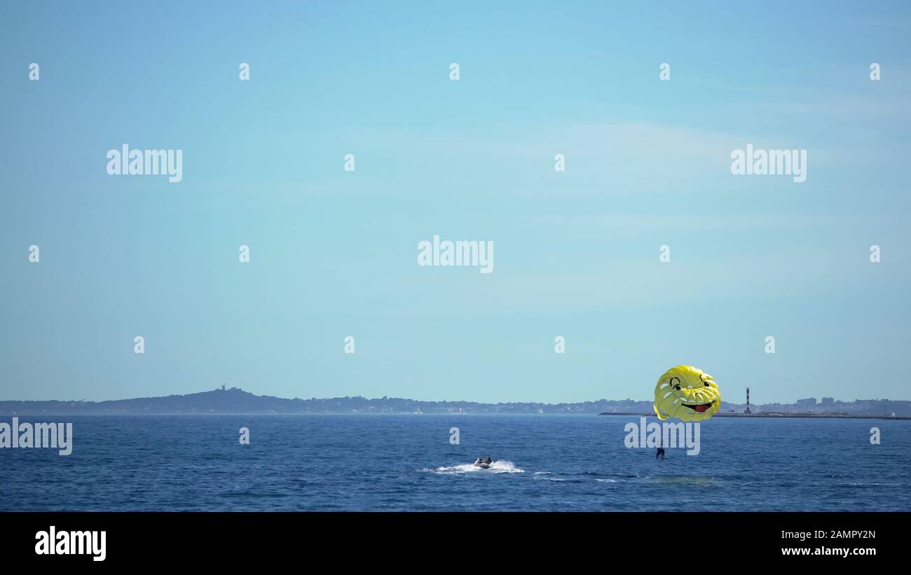 Active couple parasailing, smiley parachute flying above sea surface ...