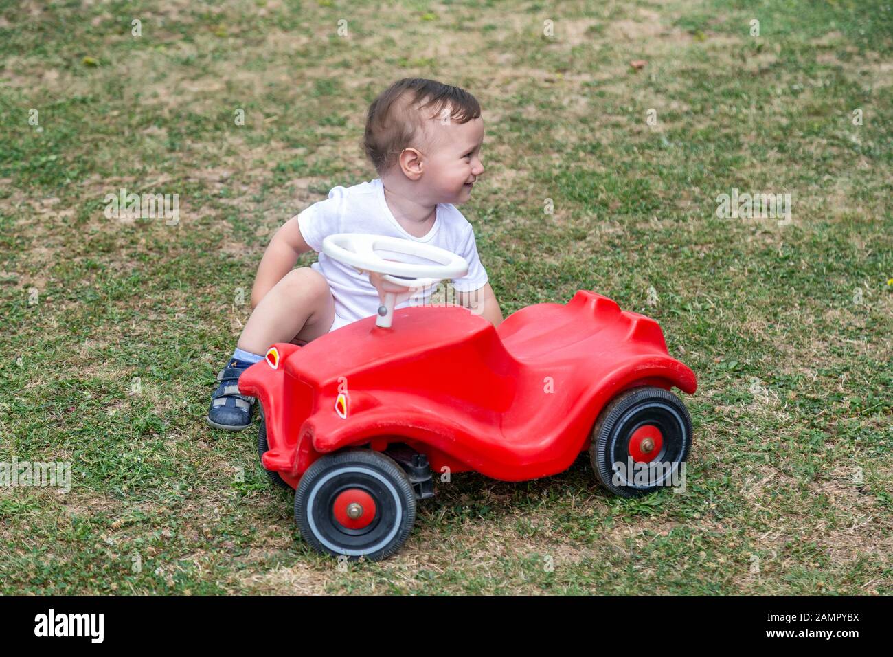 Baby boy is playing with red color toy car in the garden Stock Photo ...