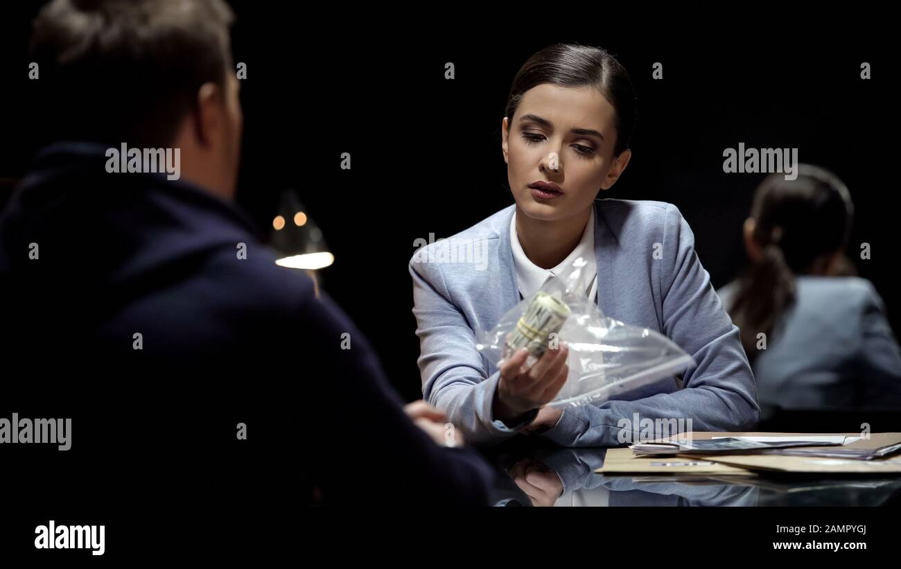 Female police officer showing to criminal cash in physical evidence ...