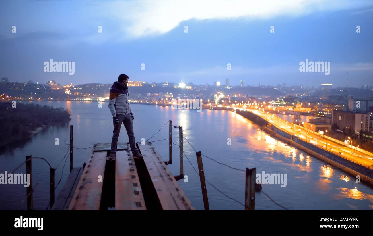 Happy man standing on top of bridge looking at beautiful night city ...