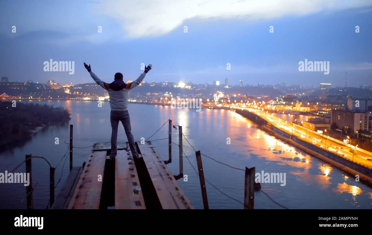 Freedom, man raising hands on top of bridge, enjoying amazing night ...