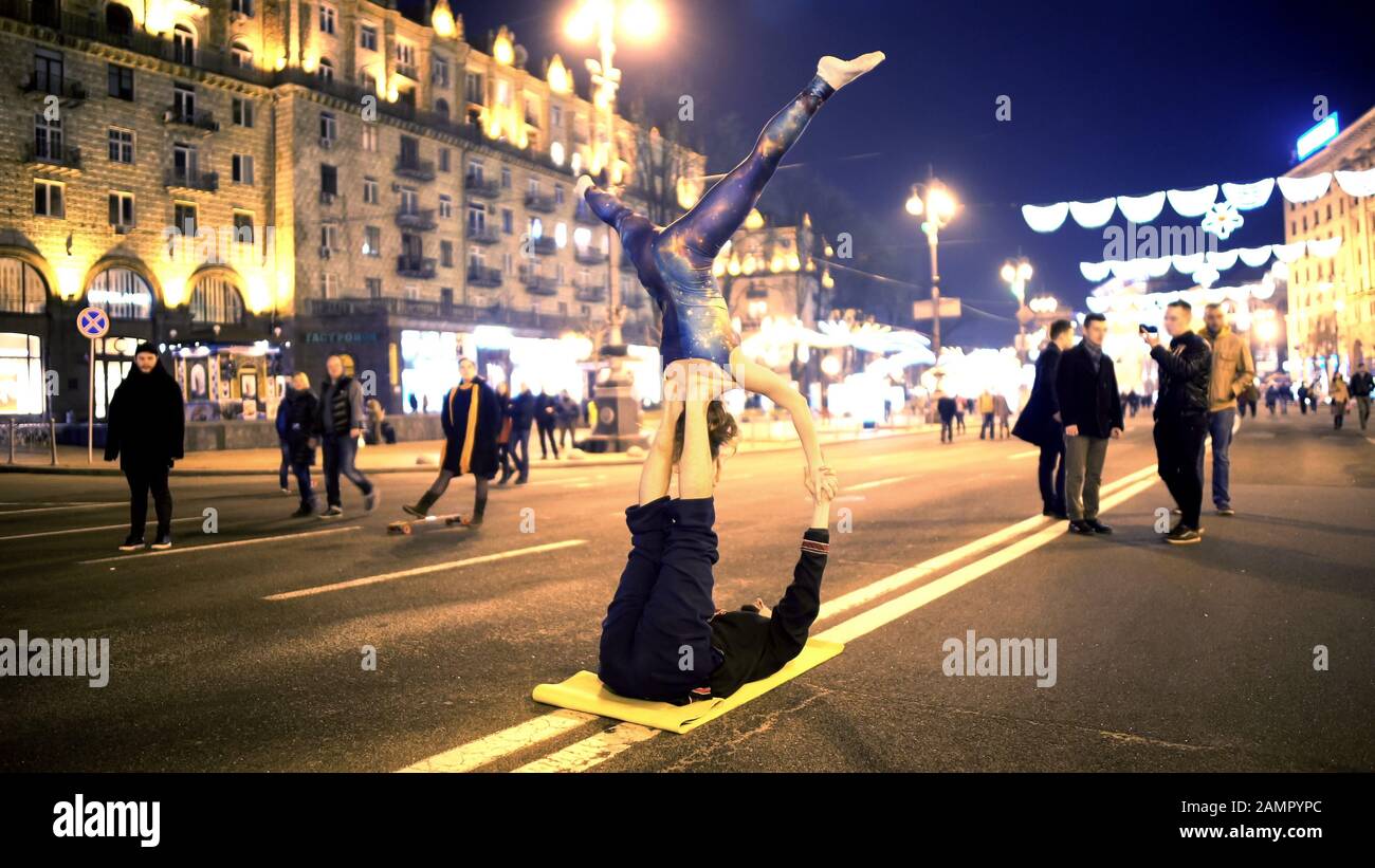 Young couple making dangerous tricks in public place, acro yoga ...