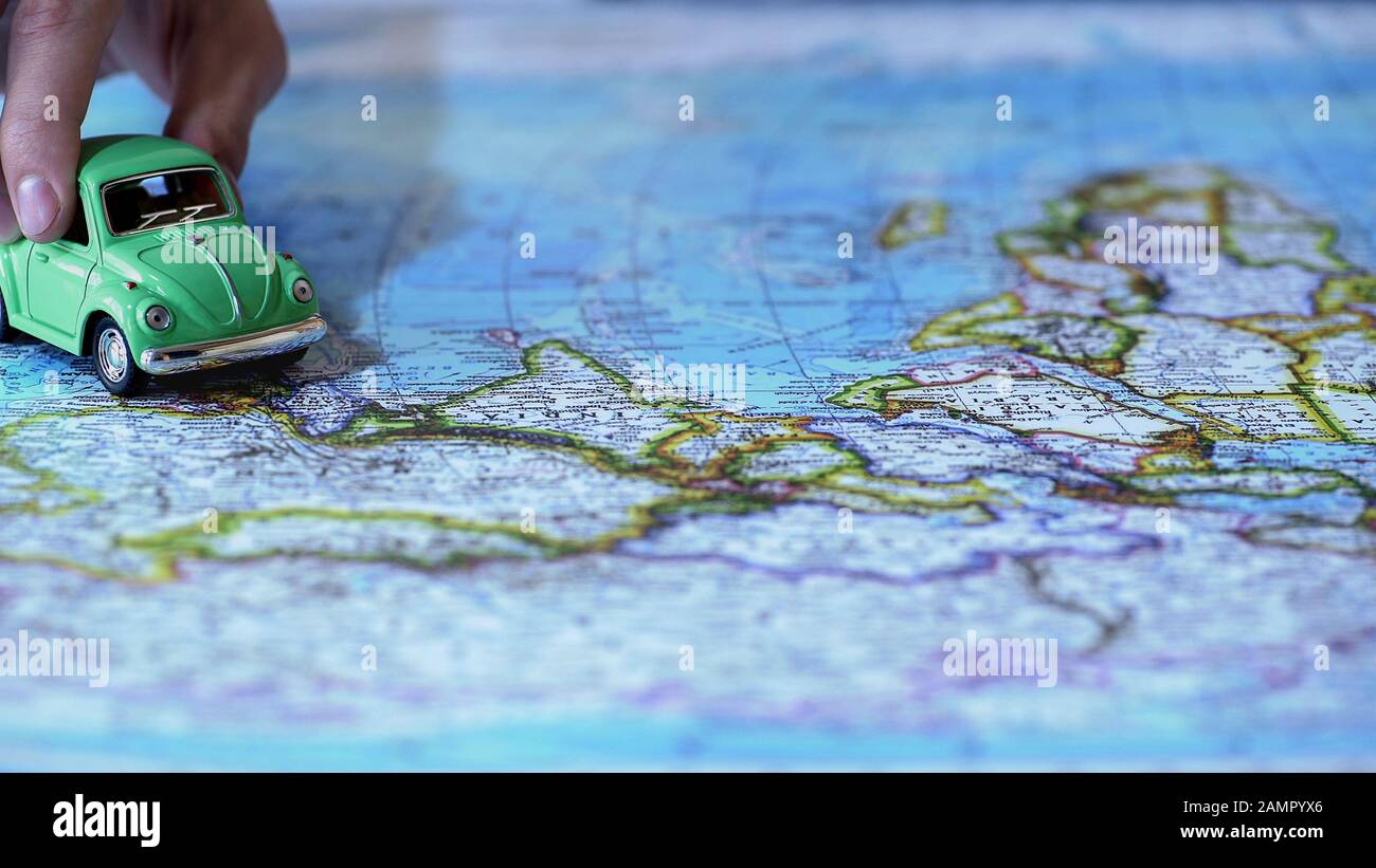 Eco friendly green car model driving across Europe on world map, travel ...