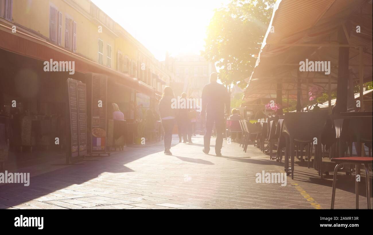 Sunny narrow street with cafes and walking tourist, summer vacation ...