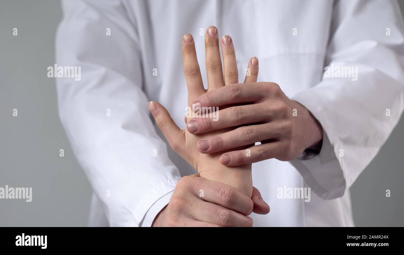 Doctor moving patient wrist, first aid in clinic, assessing severity of ...