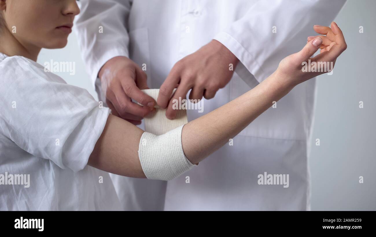 Traumatologist bandaging patient elbow, first aid for sprain in trauma ...
