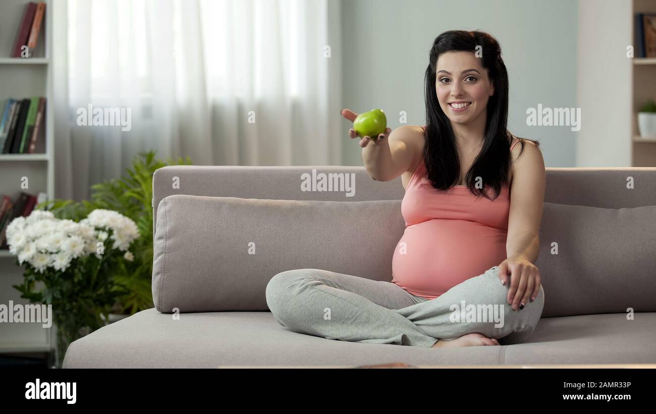 Expectant mum showing green apple, stands for healthy lifestyle, caring ...