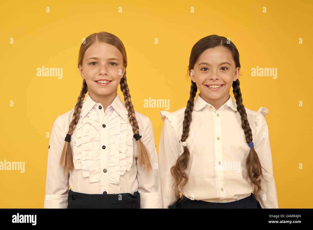 Excellent pupils. Girls perfect uniform outfit on yellow background ...