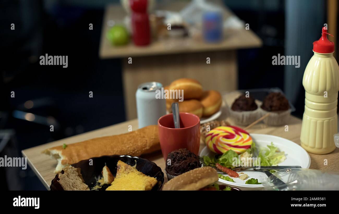 Dirty plates full of greasy junk food leftovers standing on messy table ...