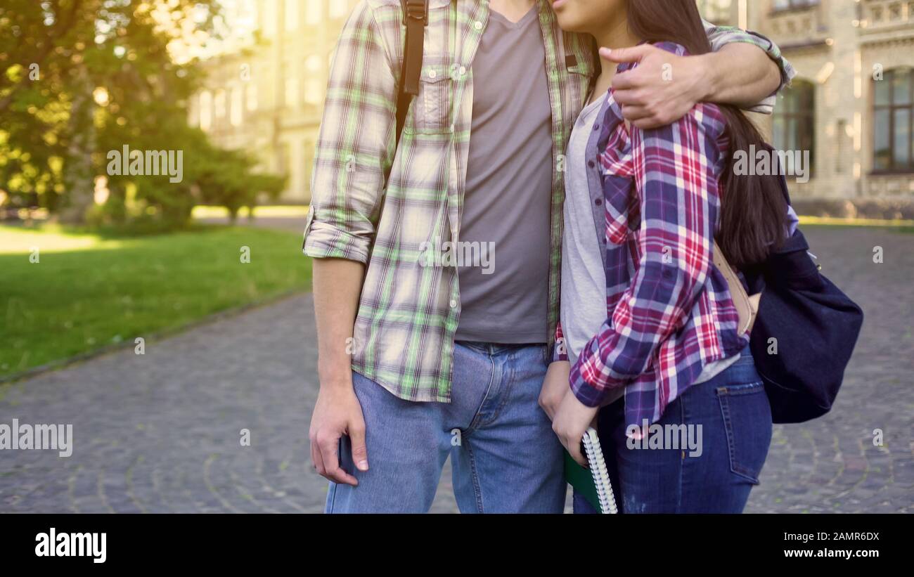 Happy couple hugging near university, students looking into promising ...