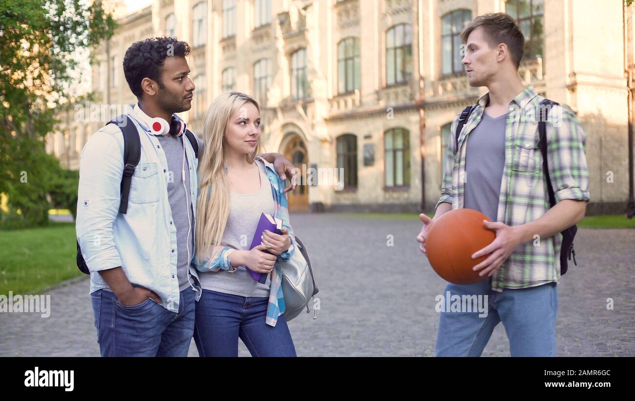 Student talking with multiracial couple near college, carefree student ...