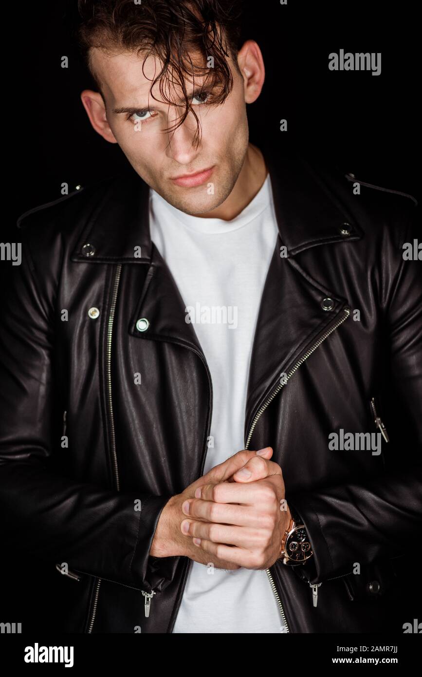 brutal man in leather jacket with clenched hands isolated on black ...