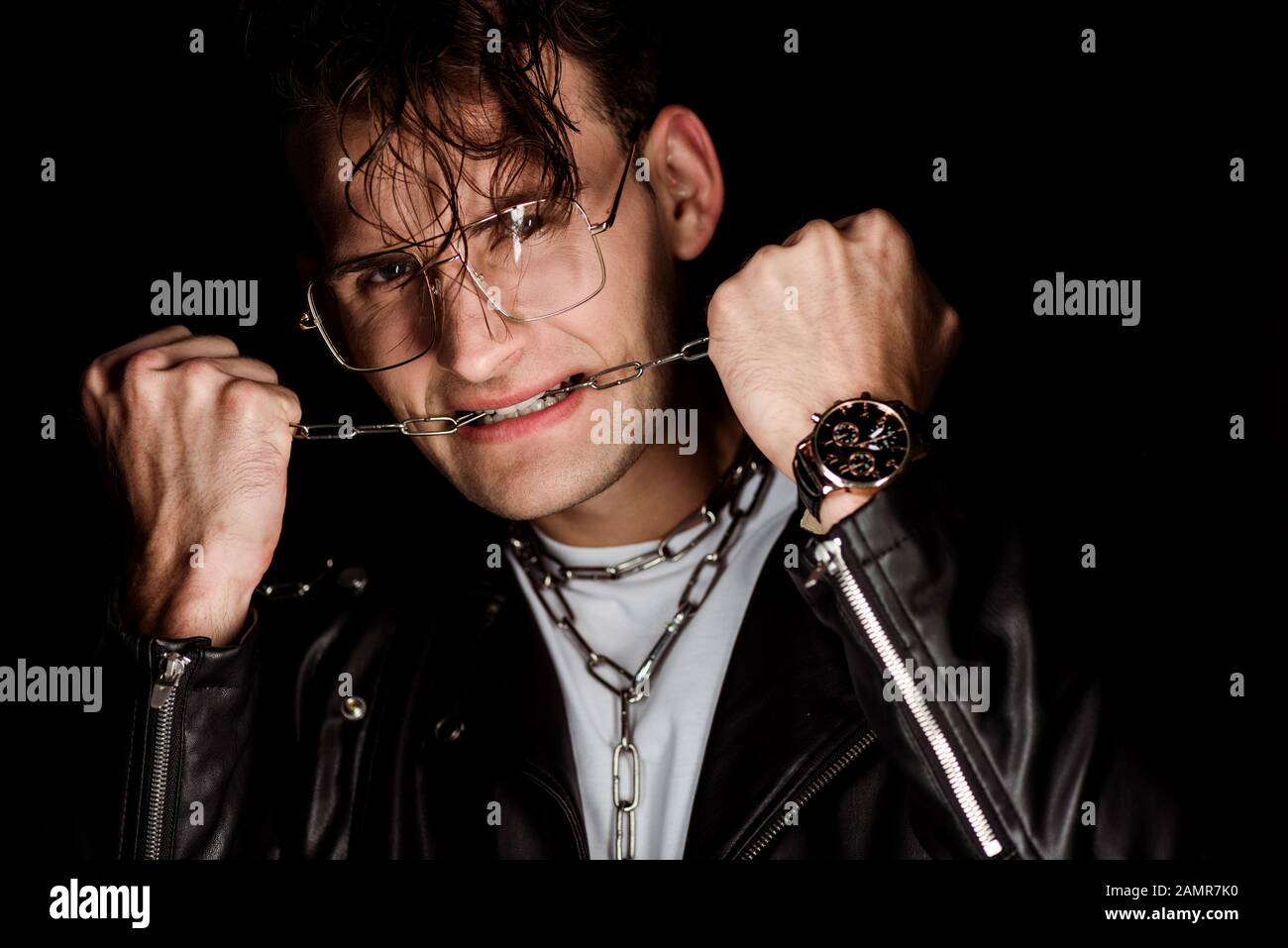 brutal man in glasses biting metallic chains isolated on black Stock ...