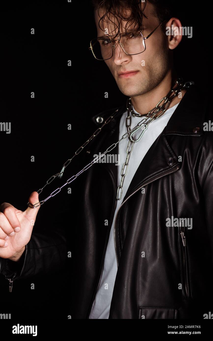 stylish man touching metallic chains on neck isolated on black Stock ...