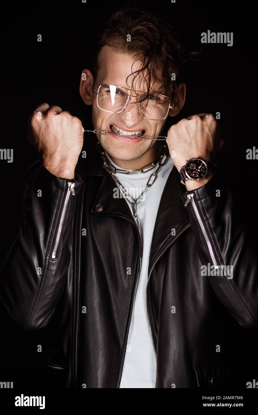 emotional man in glasses biting metallic chains isolated on black Stock ...