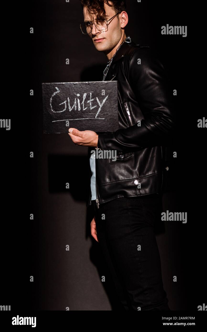 stylish man holding chalk board with guilty lettering on black Stock ...