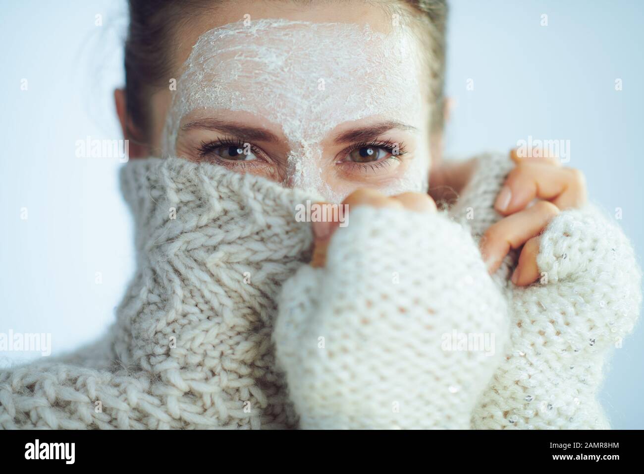 elegant woman in roll neck sweater and cardigan with white facial mask ...