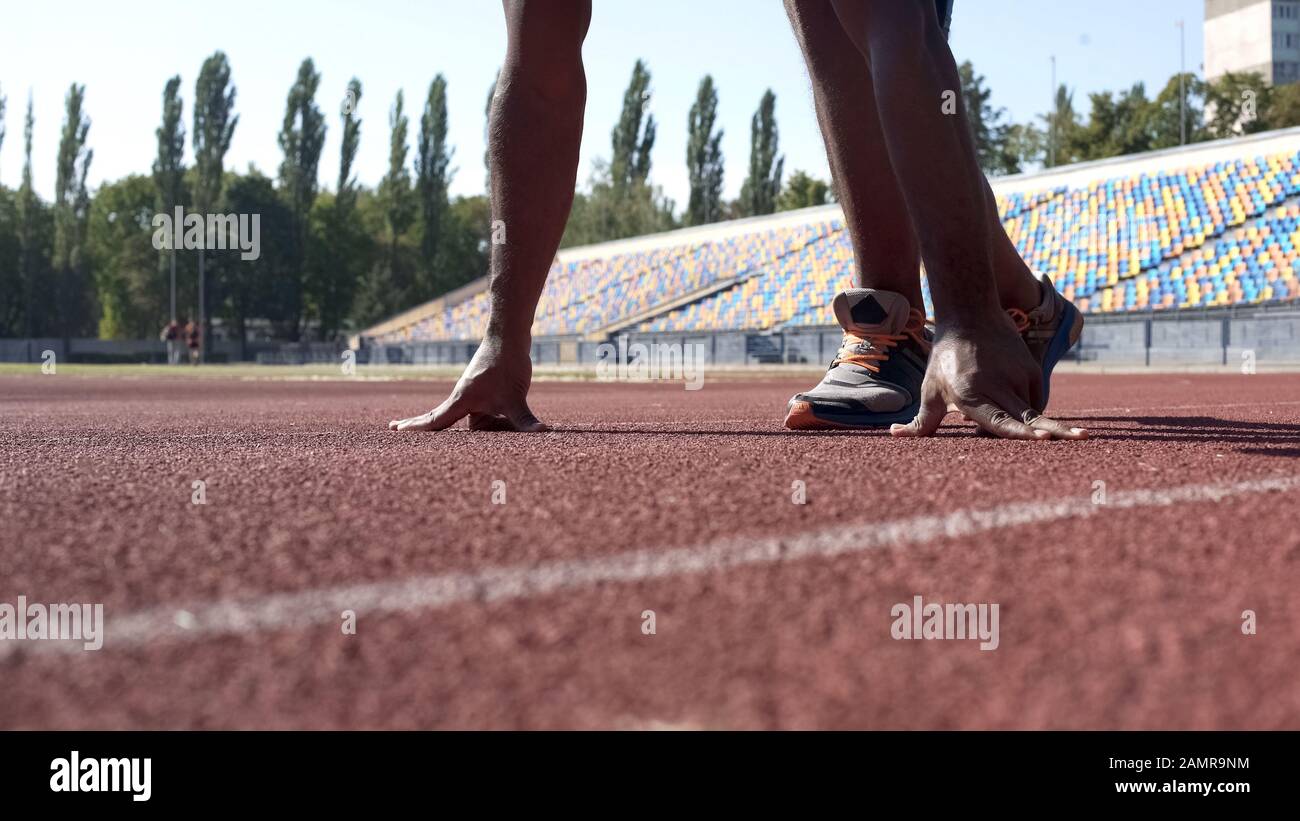 Runner in starting position on track, sportsman training before ...