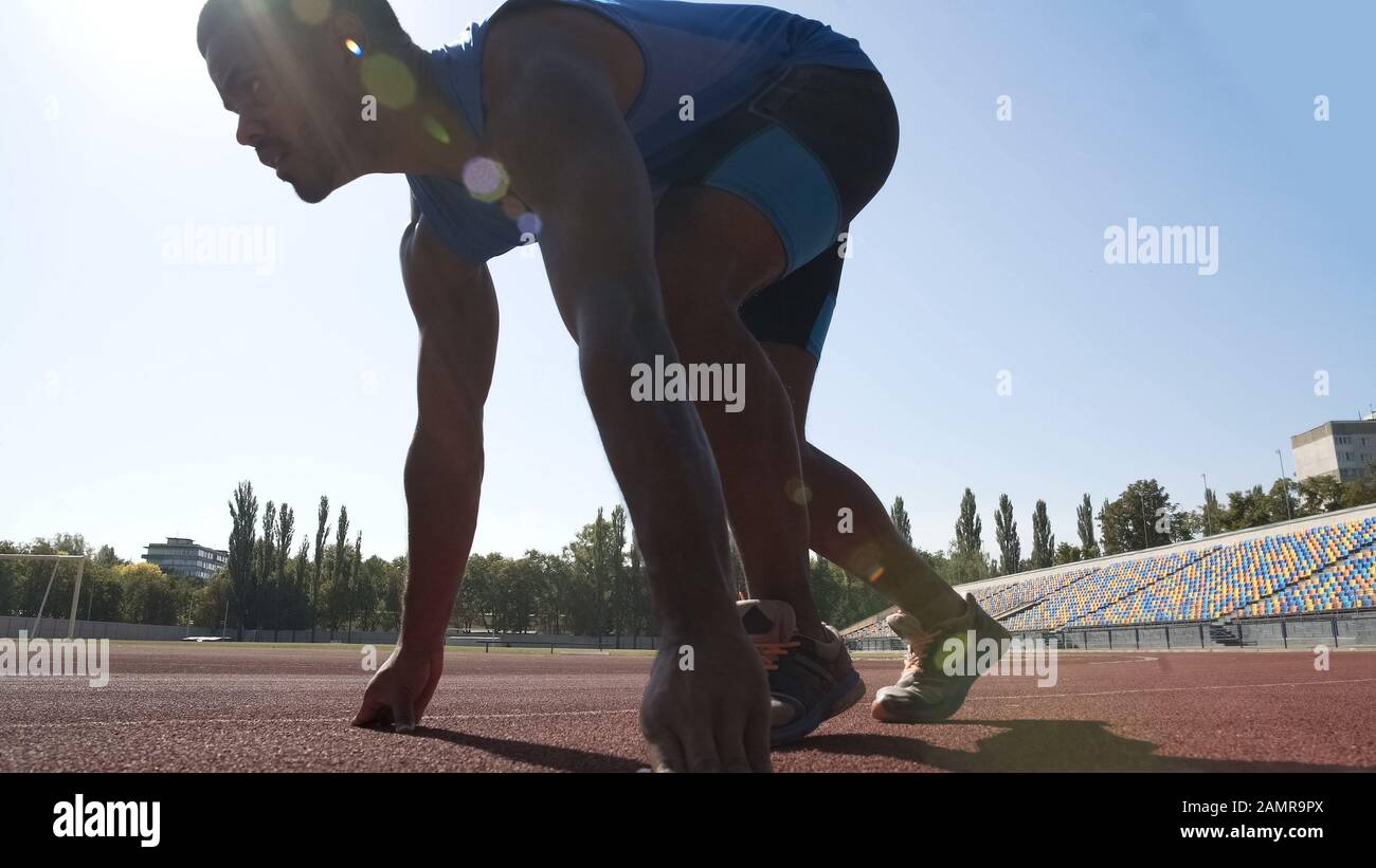 Hispanic athlete in starting position ready to run, training to improve ...