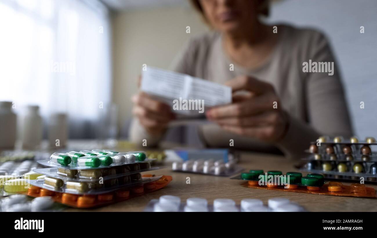 Medication lying on table, sick old woman reading prescription behind ...