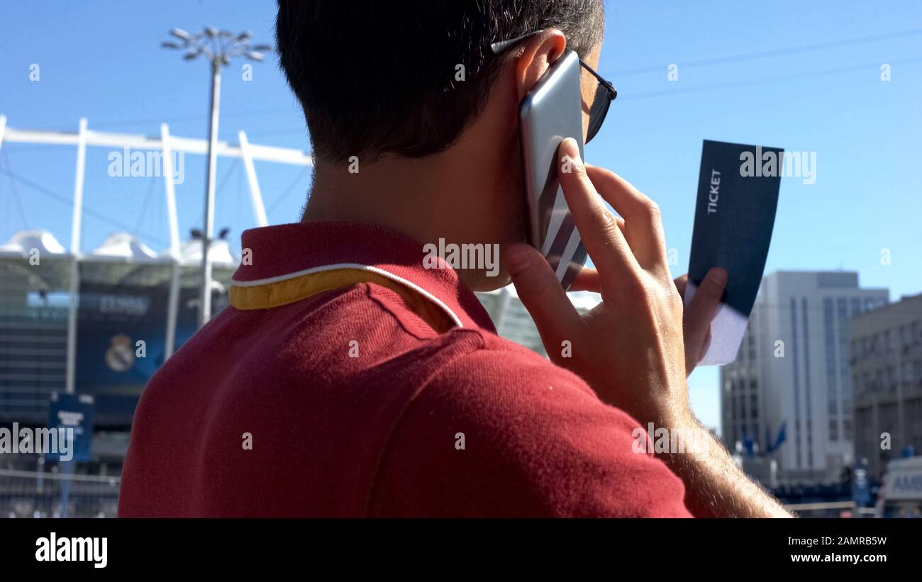 Lucky male talking on phone with football tickets in hands, happy ...