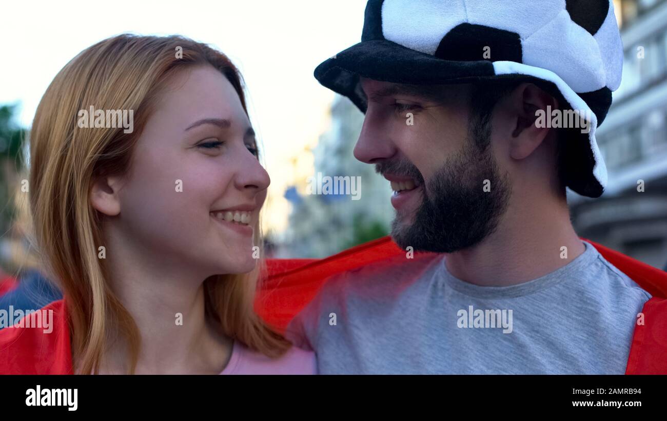 Happy football fans couple looking at each other with love and hugging ...